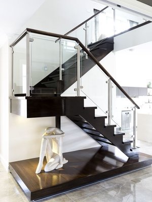 Straight wooden staircase with tempered clear glass railing indoor
