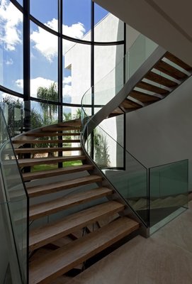 Straight wooden staircase with tempered clear glass railing indoor