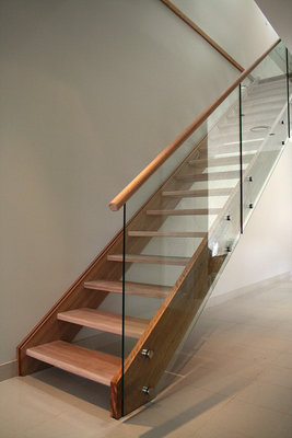 Straight wooden staircase with tempered clear glass railing indoor