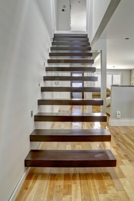 Interior floating staircase with wooden steps glass railing design